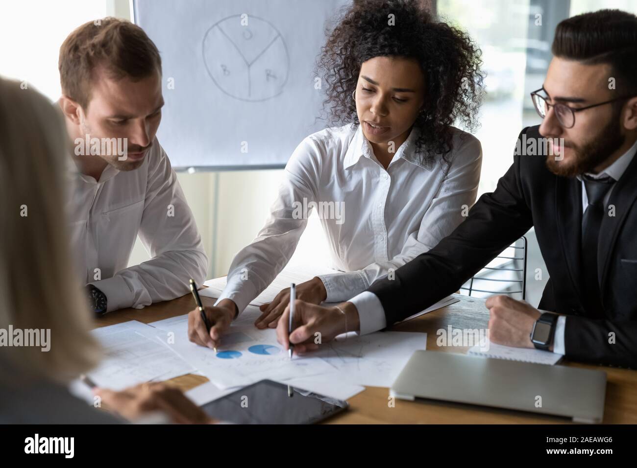 Multiracial colleagues discuss paperwork document at office briefing ...