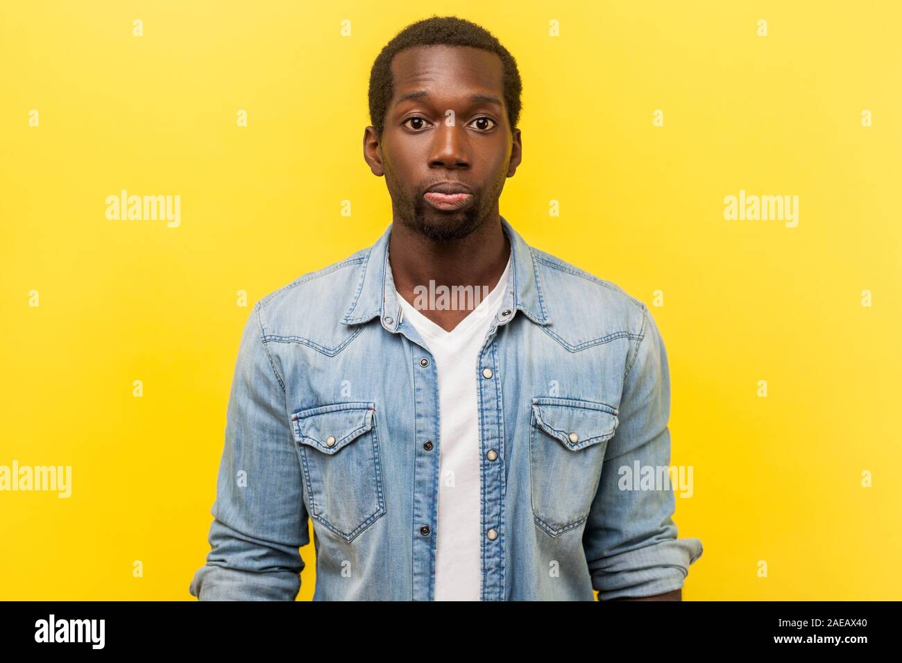 Portrait of unhappy pessimistic young man in denim casual shirt looking ...