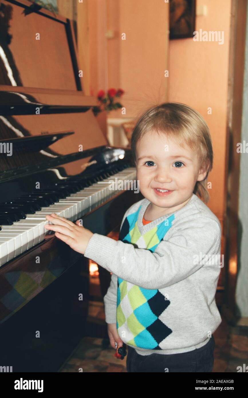 Lovely musician. Portrait of little caucasian boy playing piano at home ...
