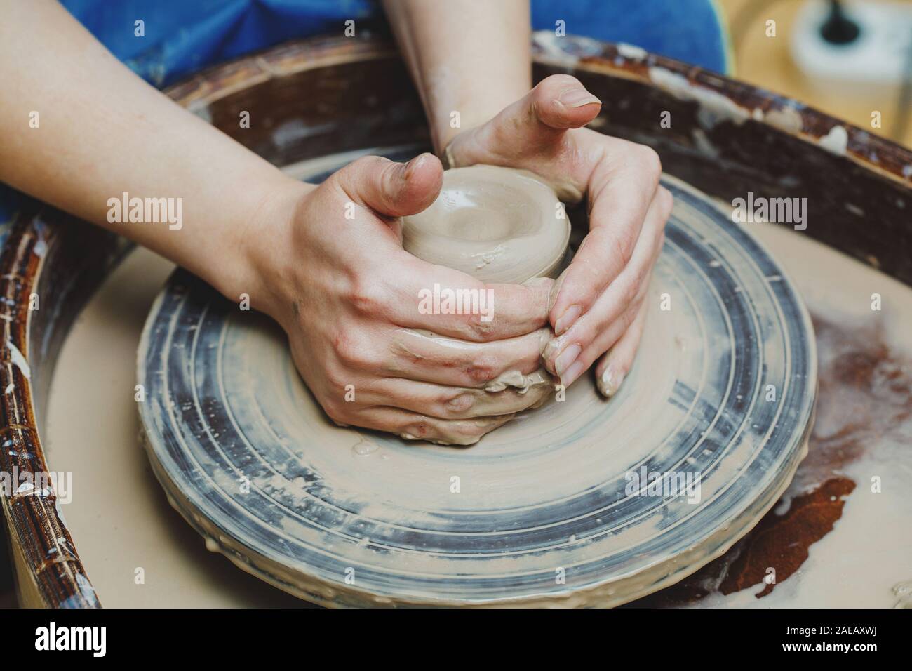 Woman hands on pottery wheel, potter at work. Craftsman artist shapes ...