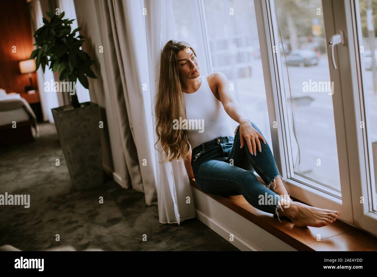 Beautiful young woman sitting by the window in apartment Stock Photo ...