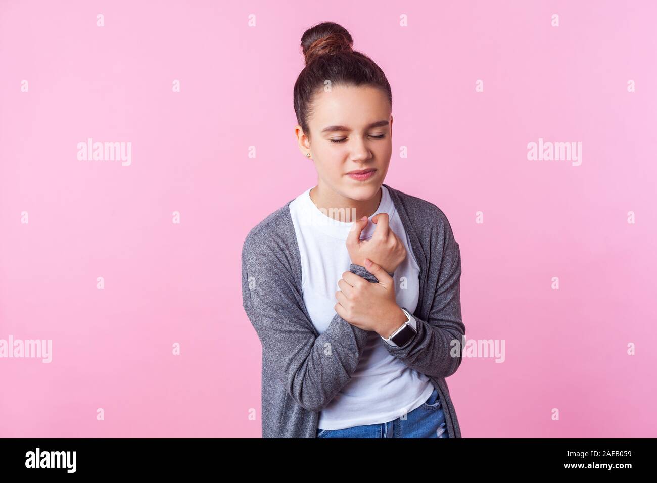 Injured hand. Portrait of upset brunette teen girl with bun hairstyle ...