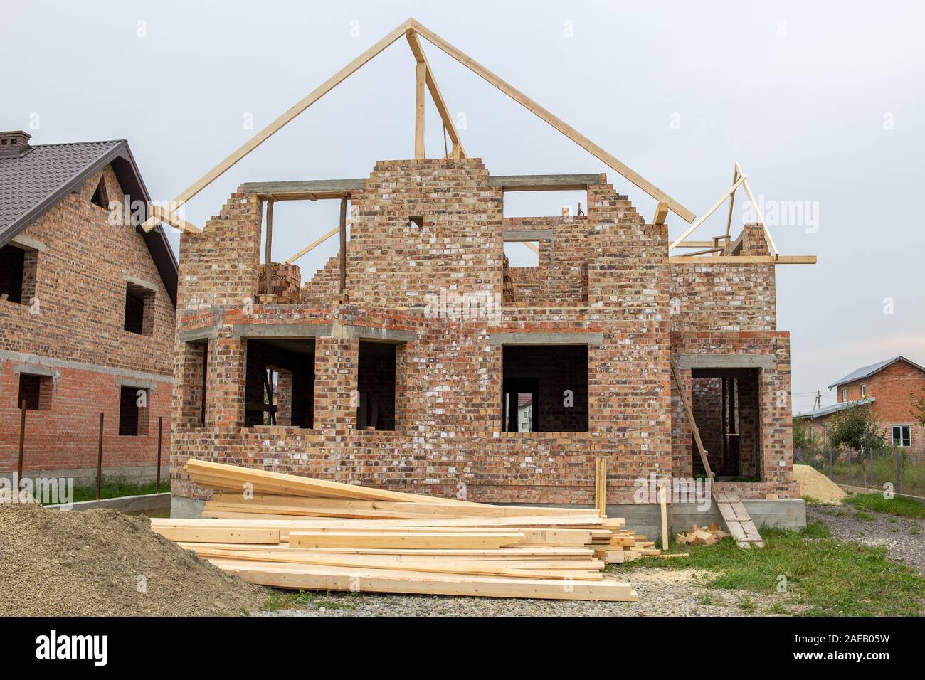 Unfinished brick house with wooden roof structure under construction ...