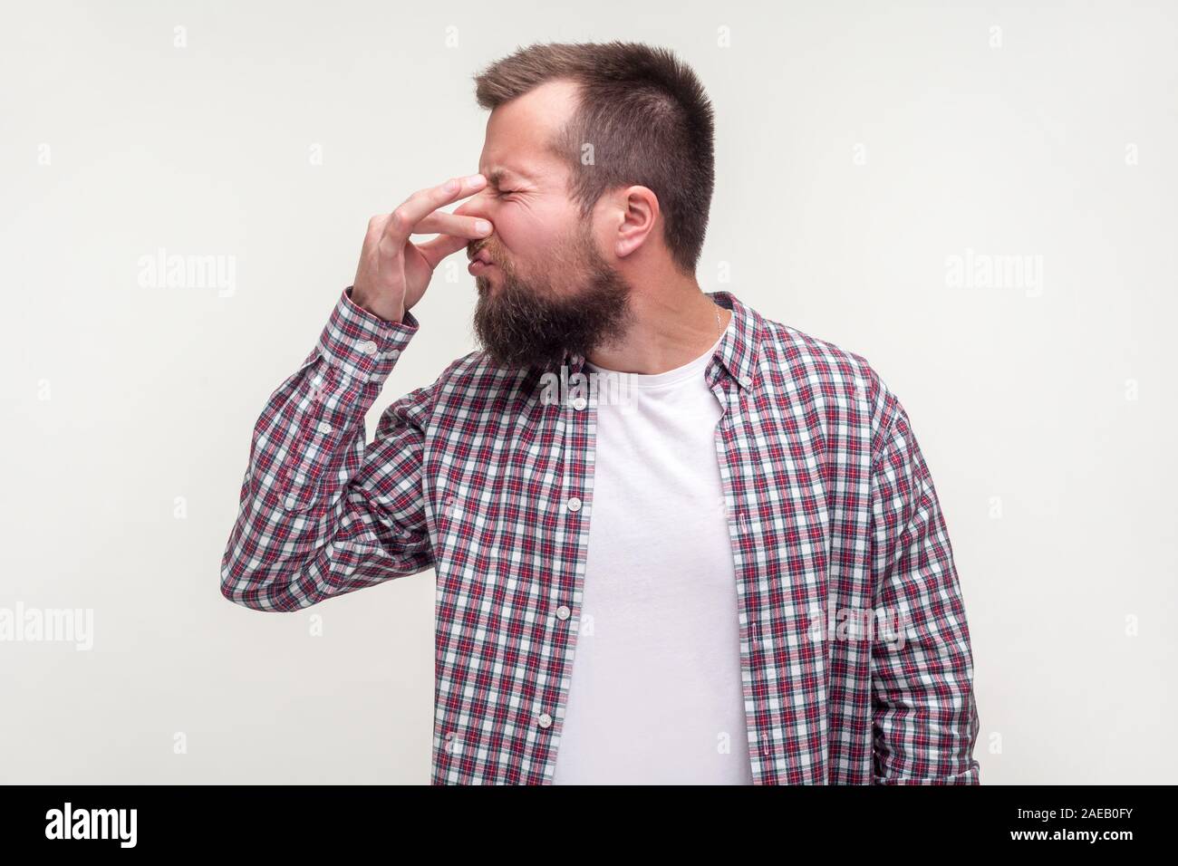 Portrait of dissatisfied bearded man in casual plaid shirt pinching ...