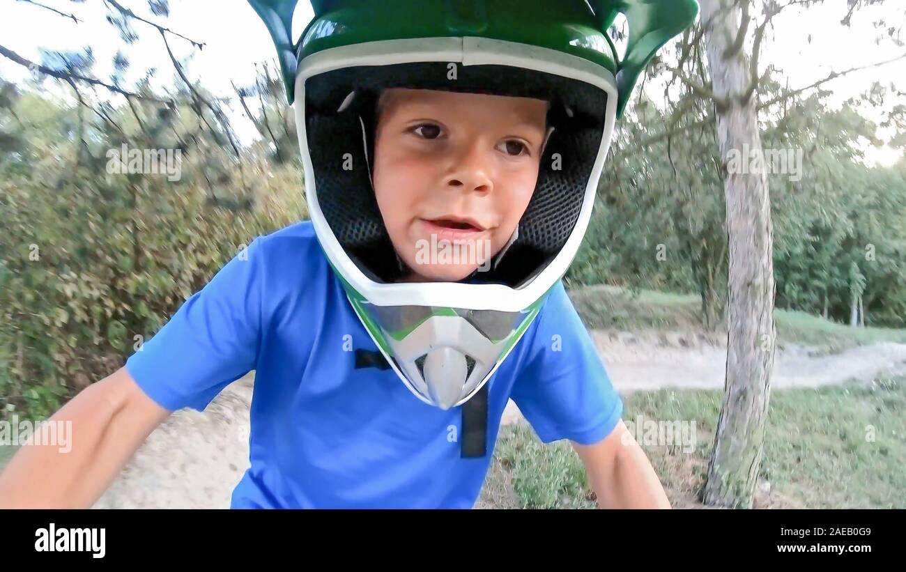 A young boy enjoys a ride on BMX track. Close-up of helmet and rider's ...