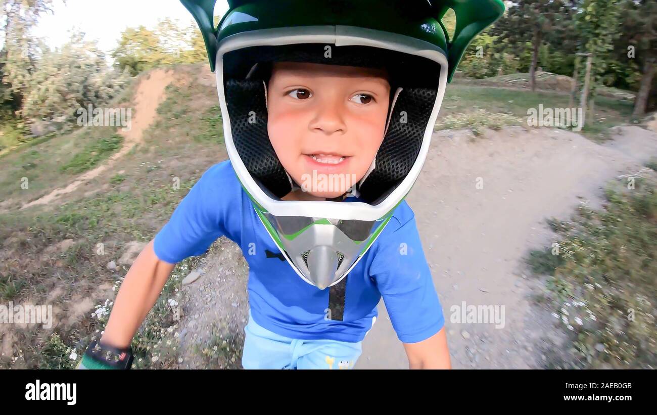 A young boy enjoys a ride on BMX track. Close-up of helmet and rider's ...