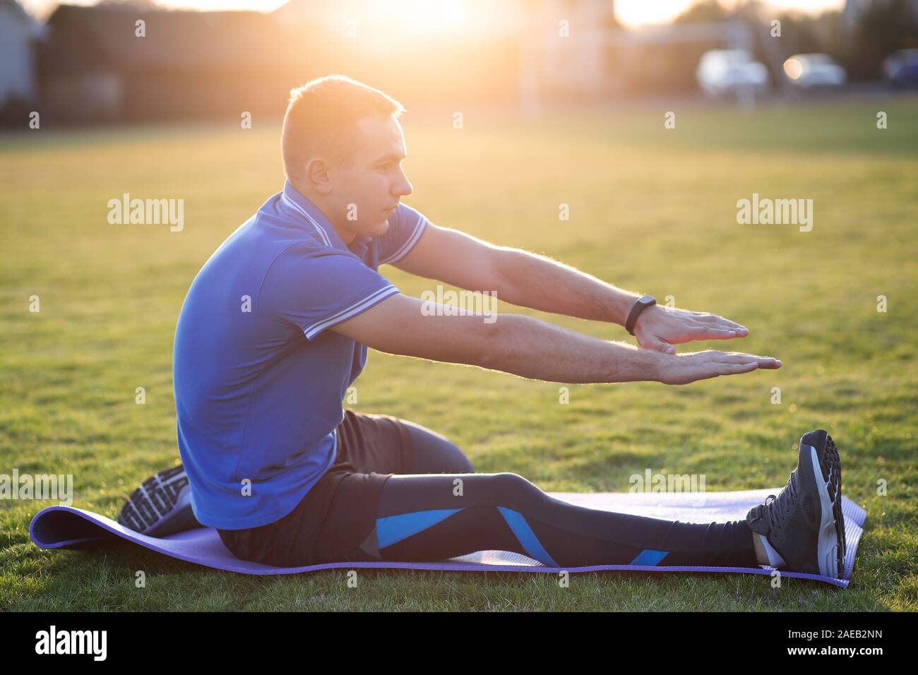 Young sportive man doing stretching exercises before running in morning ...