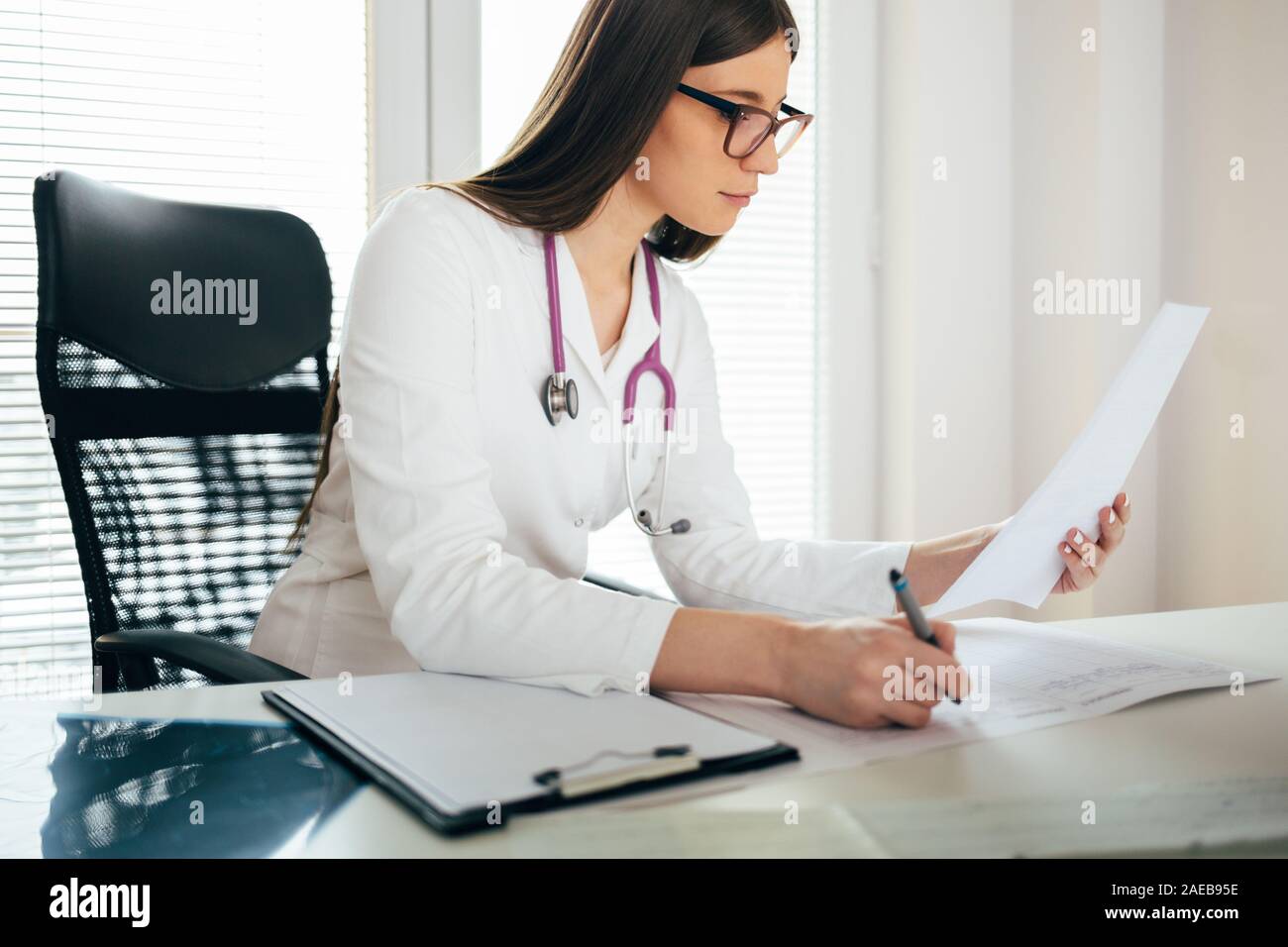 Young female doctor at office desk Stock Photo - Alamy
