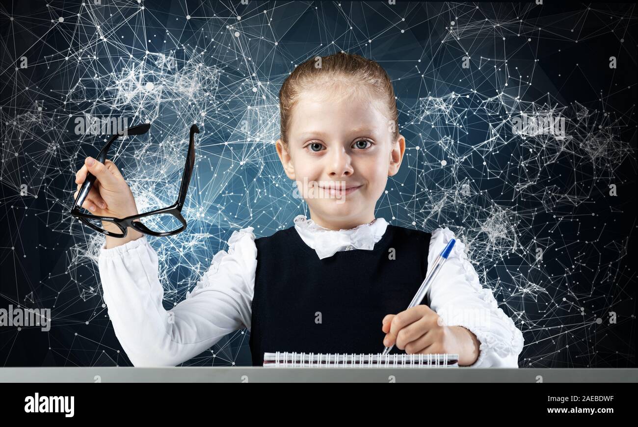 Smiling little girl in schoolwear doing homework Stock Photo - Alamy