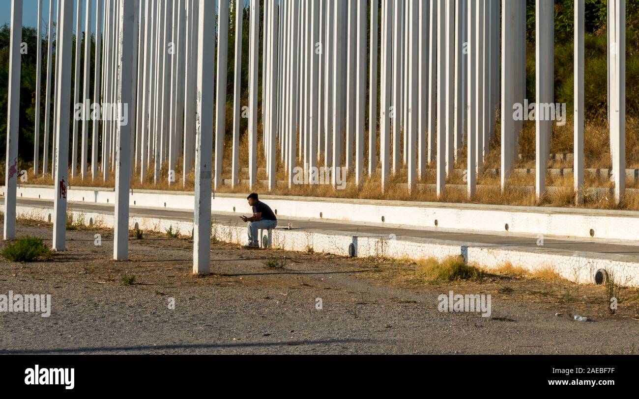 Man sitting alone on step in front of monument at 2004 Olympic Complex ...
