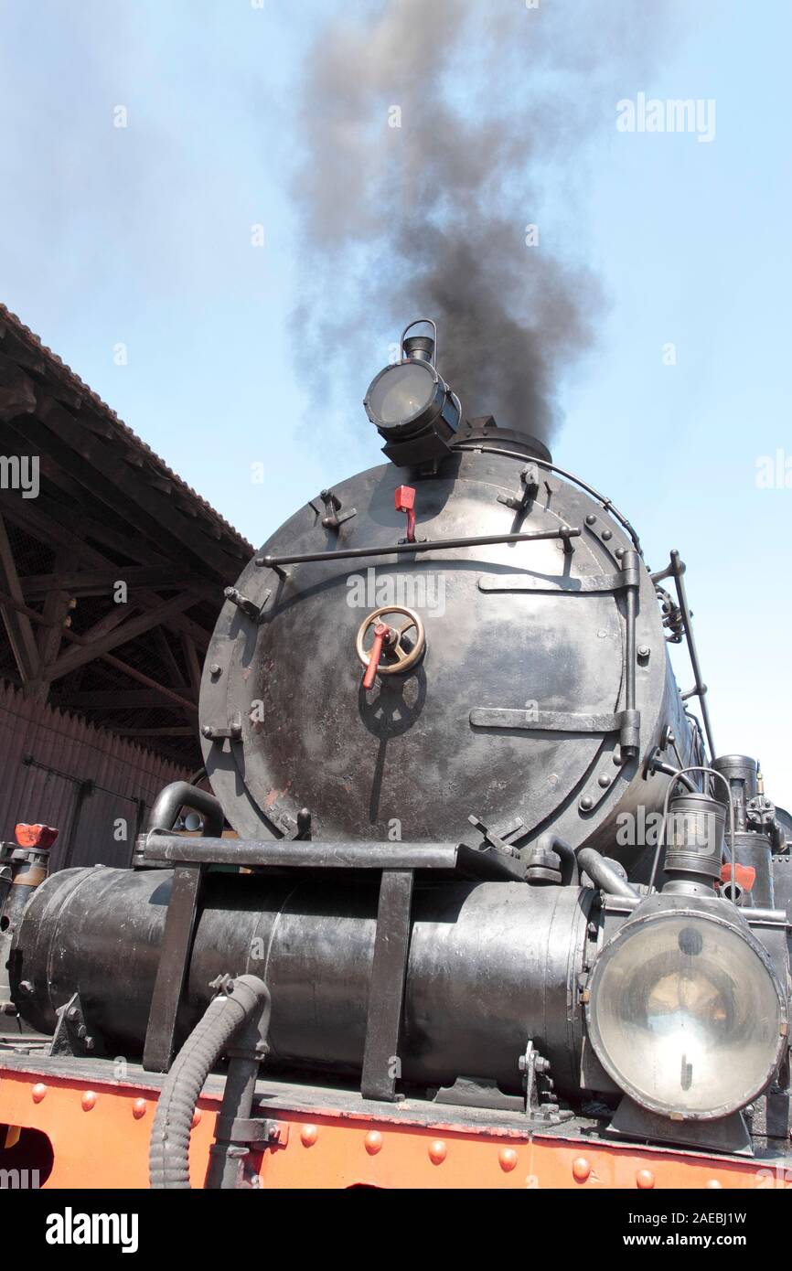 Old steam locomotive seeing smoke against blue sky Stock Photo - Alamy