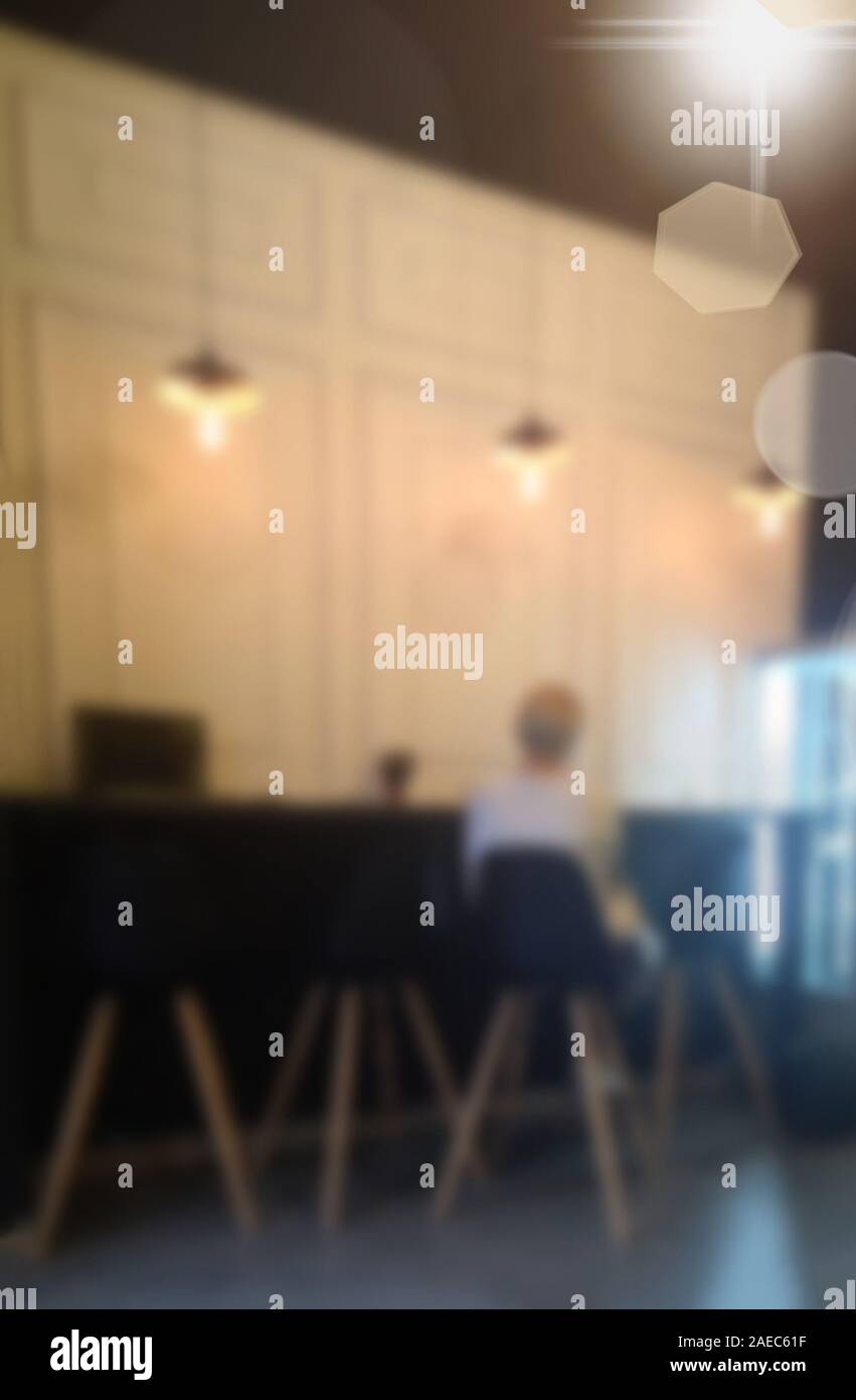 Blurred view of alone woman in modern cafe with trendy interior. Back ...