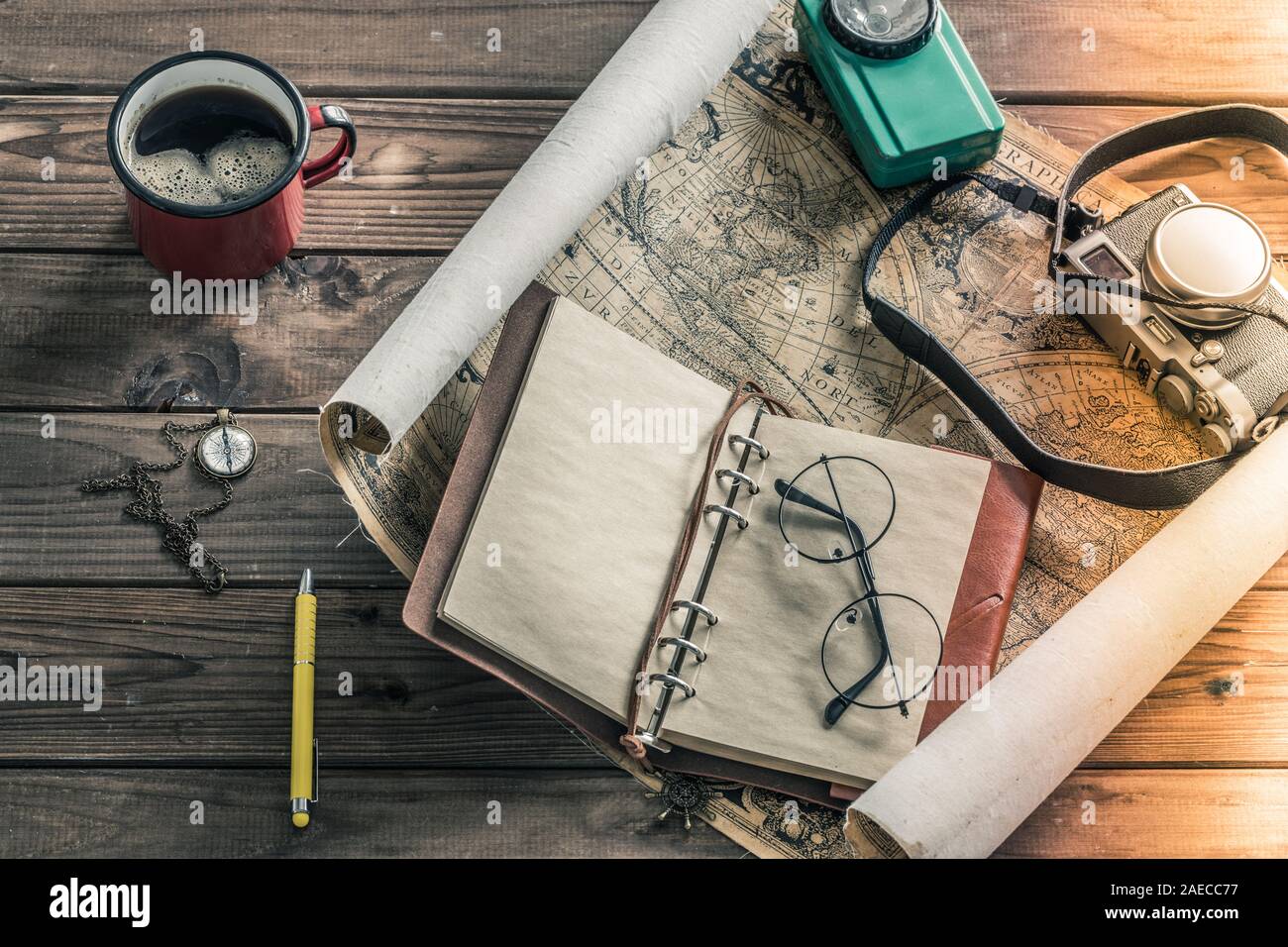 A map spread out on the table with a cup of hot tea and useful items ...