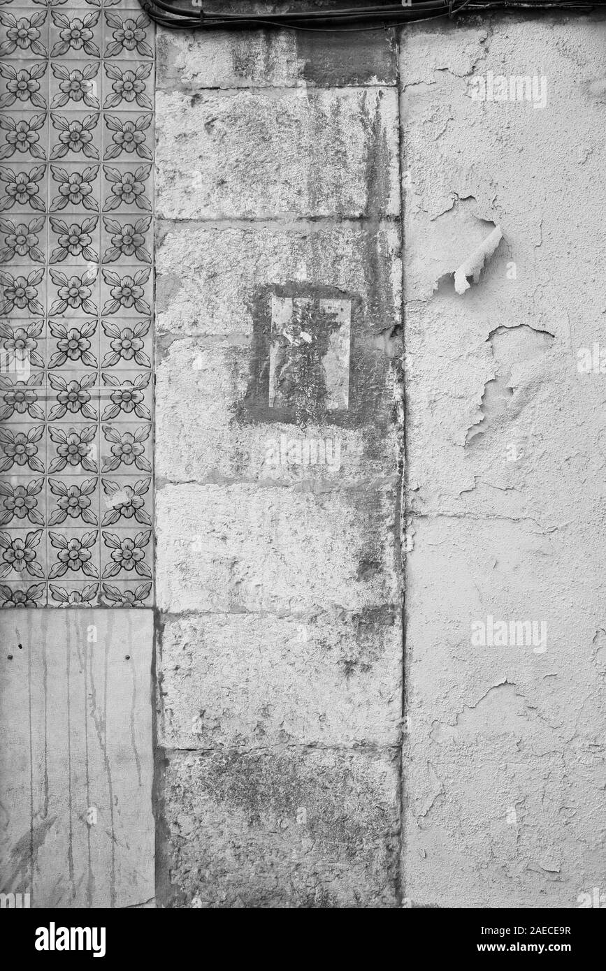 Front view of an old wall with faded ceramic tiles (azulejos), dirty ...