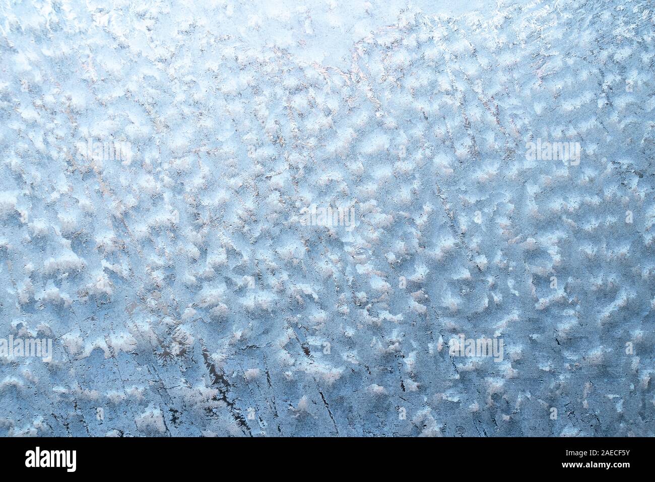 Surface of a winter frozen window is backlit by the sun outside ...