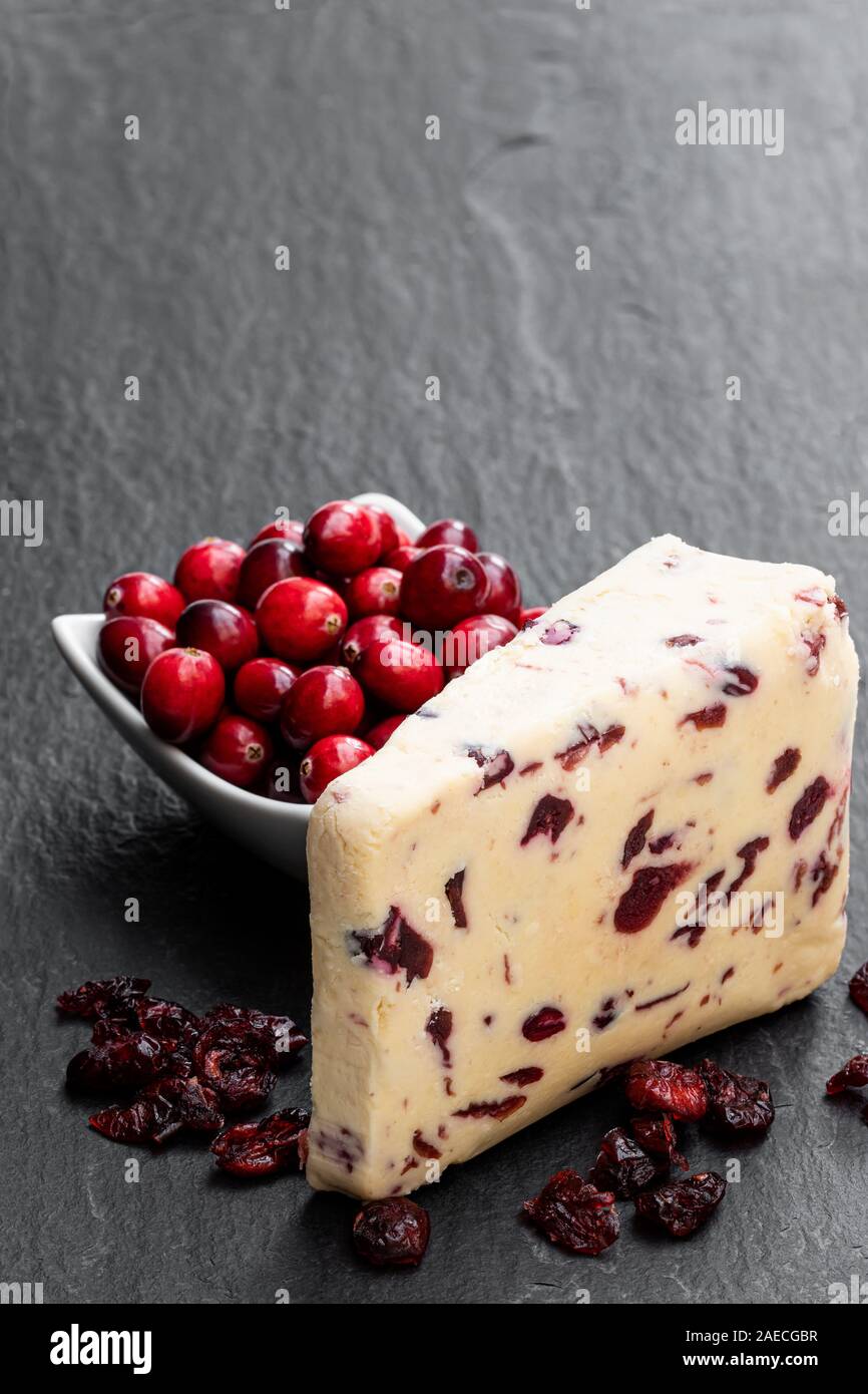 Cranberry cheddar cheese with fresh cranberry on black stone background ...