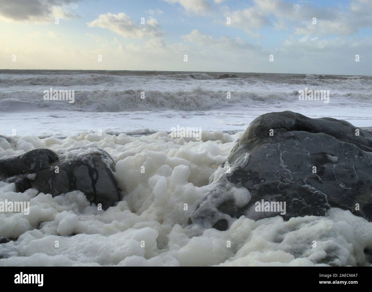 windy weather causing sea foam to wash up on the beach between two ...