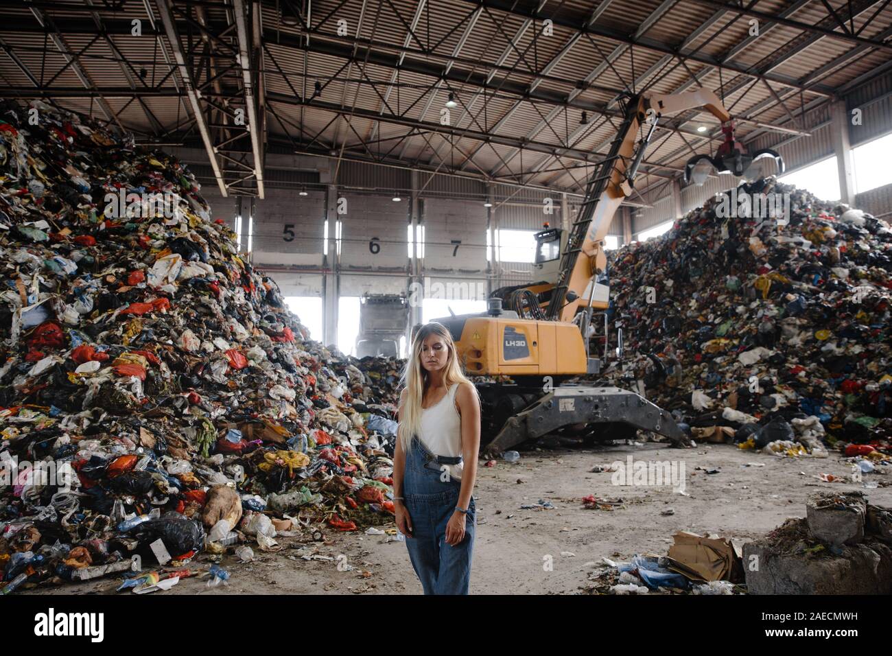 Nature pollution activist at a huge trash dump - Young blonde woman ...