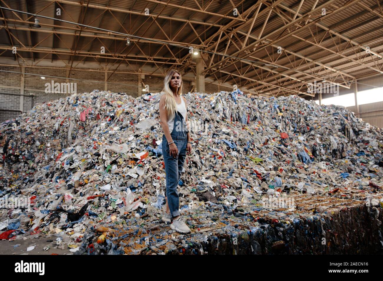 Nature pollution activist at a huge trash dump - Young blonde woman ...
