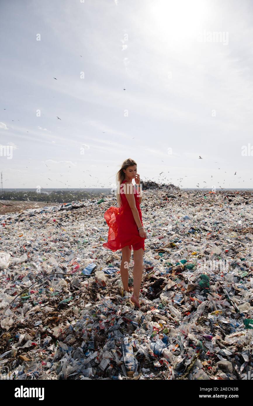 Nature pollution activist at a huge trash dump outdoors - Young blonde ...