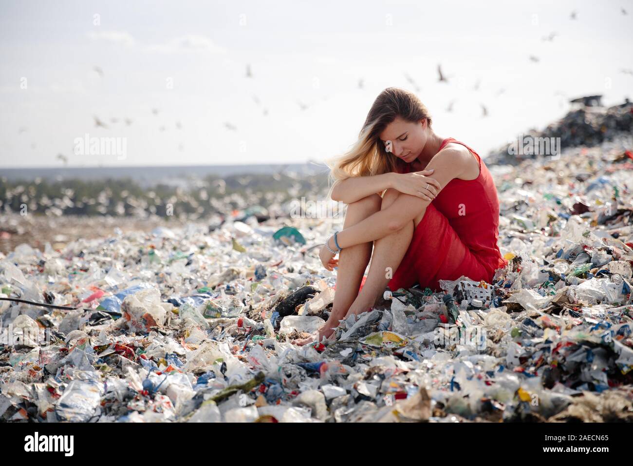 Nature pollution activist at a huge trash dump outdoors - Young blonde ...