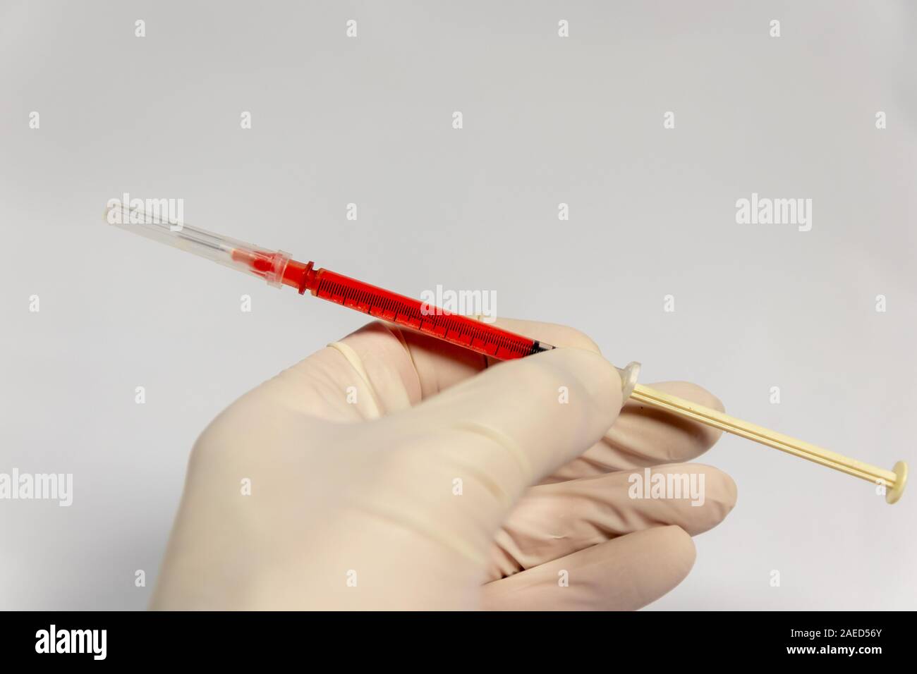 Doctor holding syringe filled with red fluid Stock Photo - Alamy