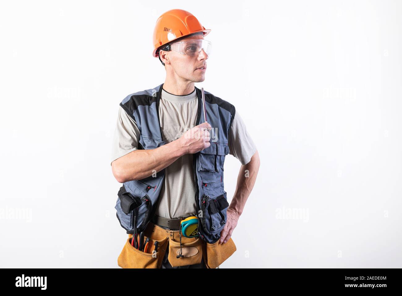 A builder in a helmet makes visual measurement with a marking pencil ...