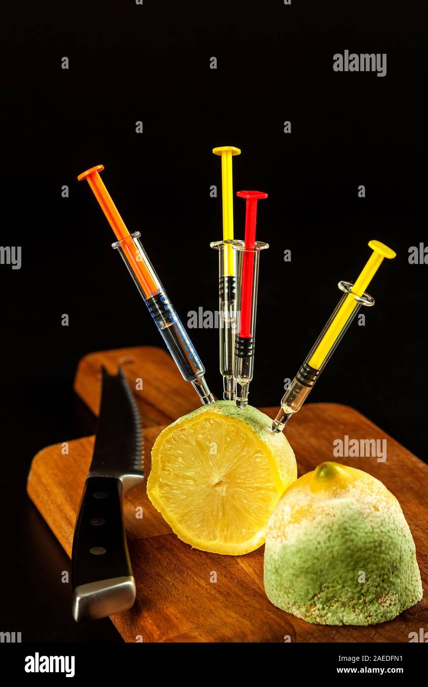 Moldy lemon with syringe. Chemistry in food. Unhealthy food. Decayed ...