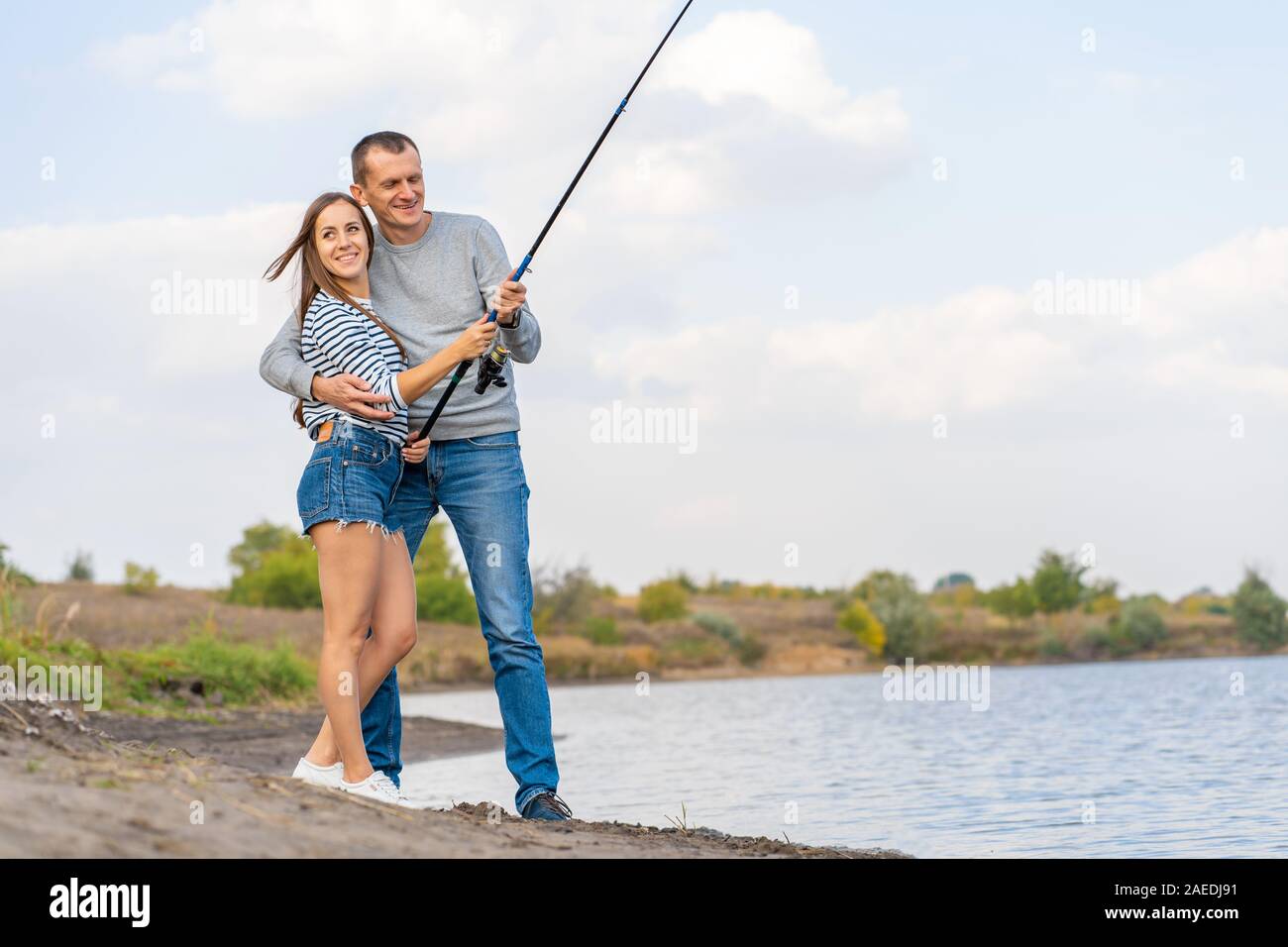 Happy young couple fishing by lakeside Stock Photo - Alamy