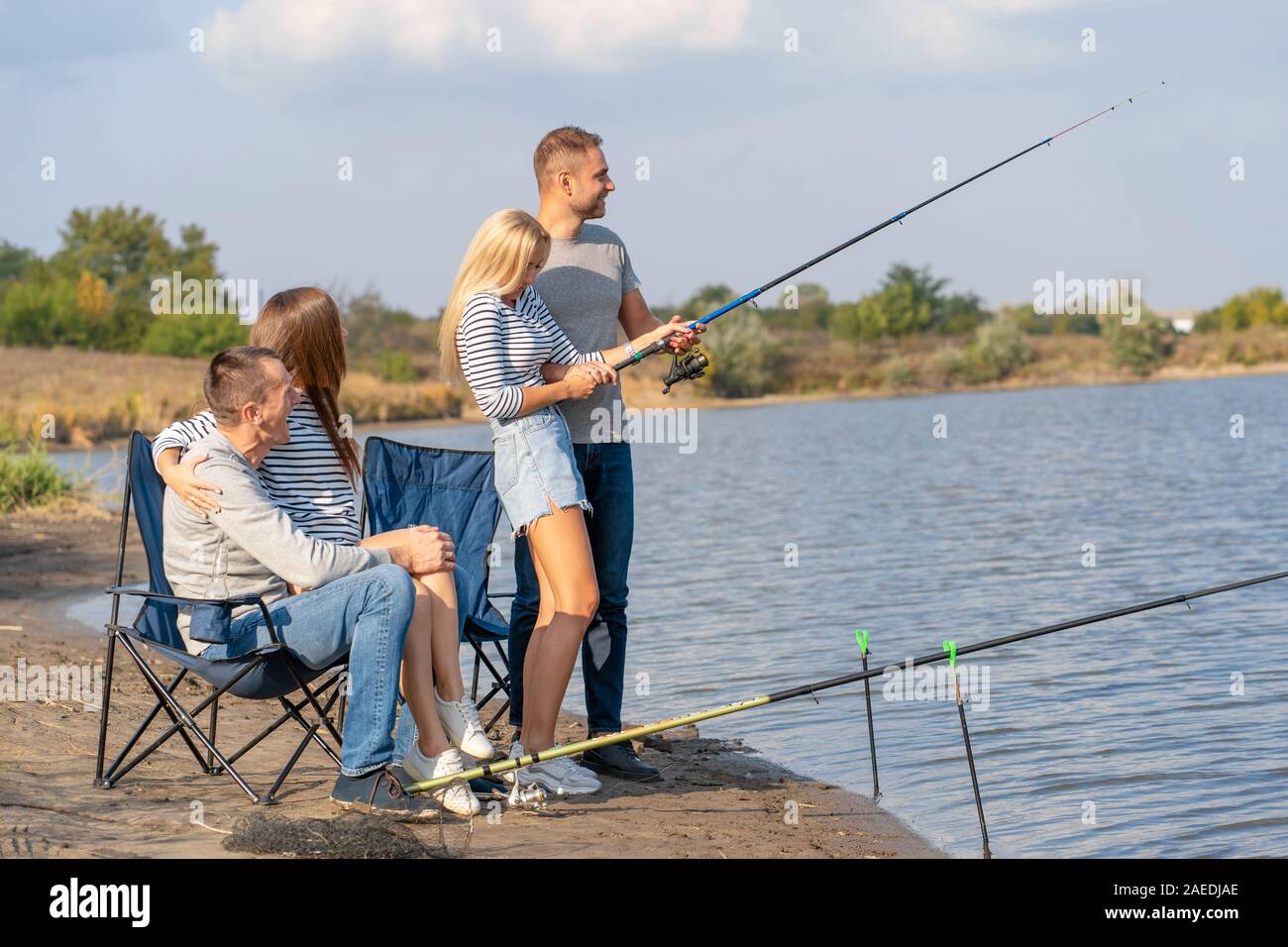 Group of young friends fishing on the pier by lakeside Stock Photo - Alamy