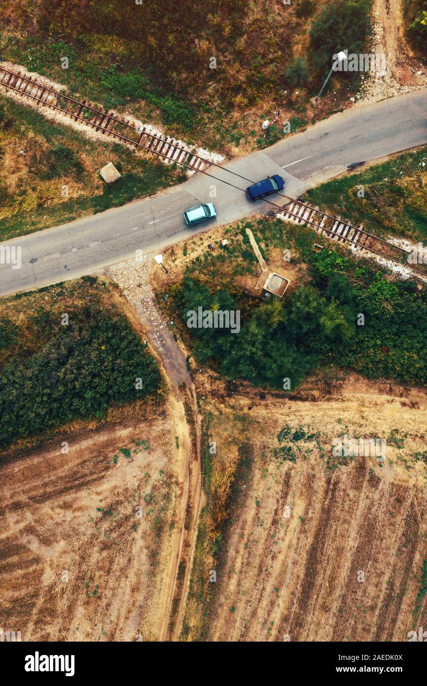 Aerial view of two cars passing railway on level crossing with boom ...