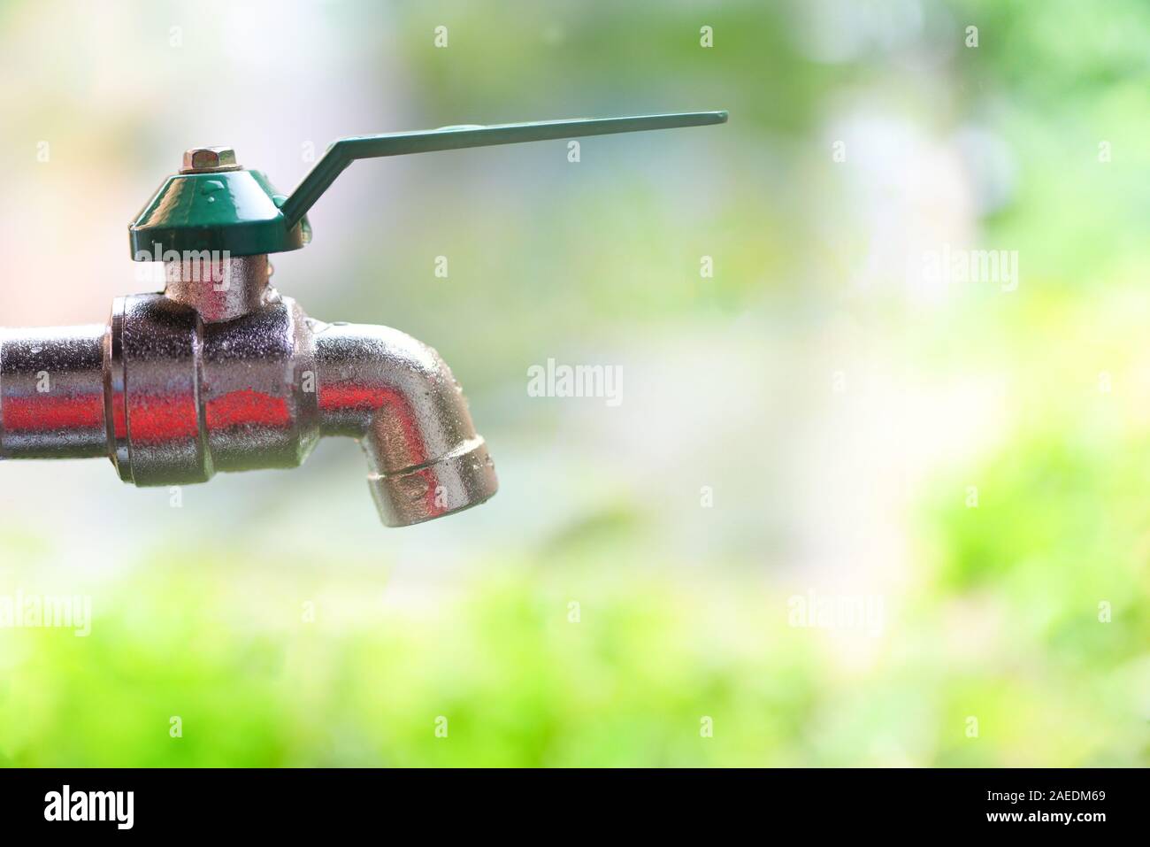 faucet water dripping with nature green background / water savings ...