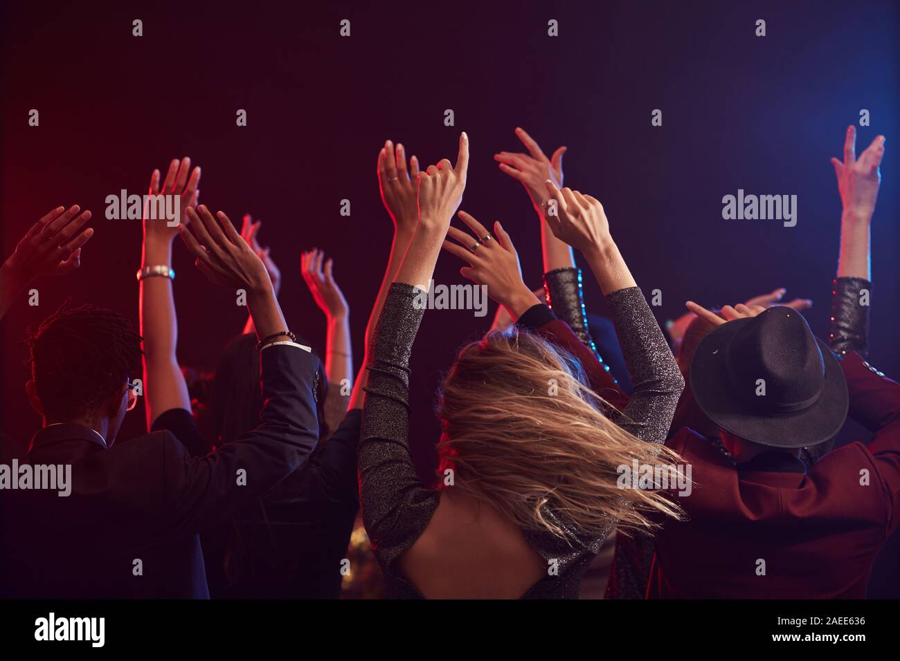 Back view of young people jumping and raising hands while enjoying ...
