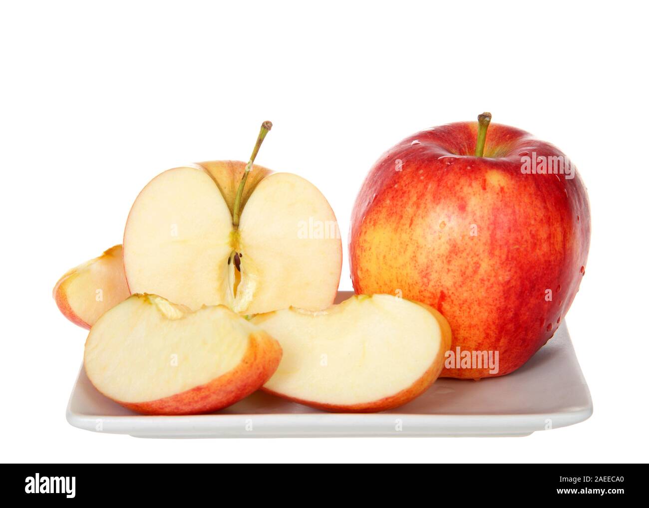 One whole gala apple with one sliced on a small rectangular plate ...