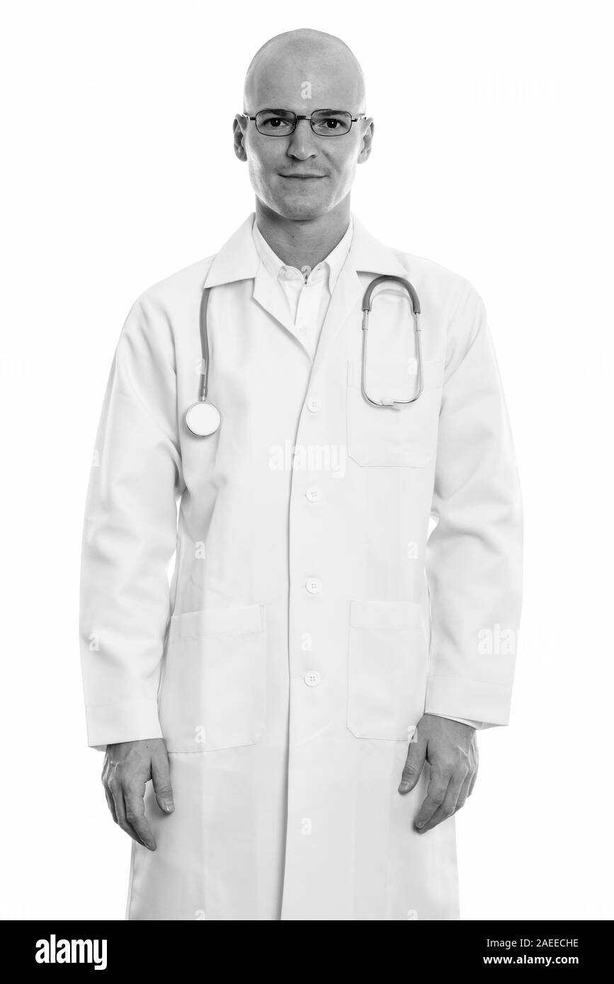 Studio shot of young handsome bald man doctor standing while wearing ...