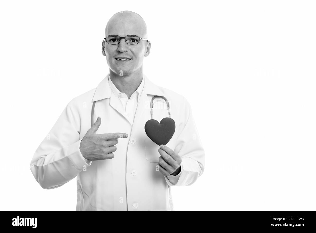 Studio shot of young happy bald man doctor smiling while holding and ...