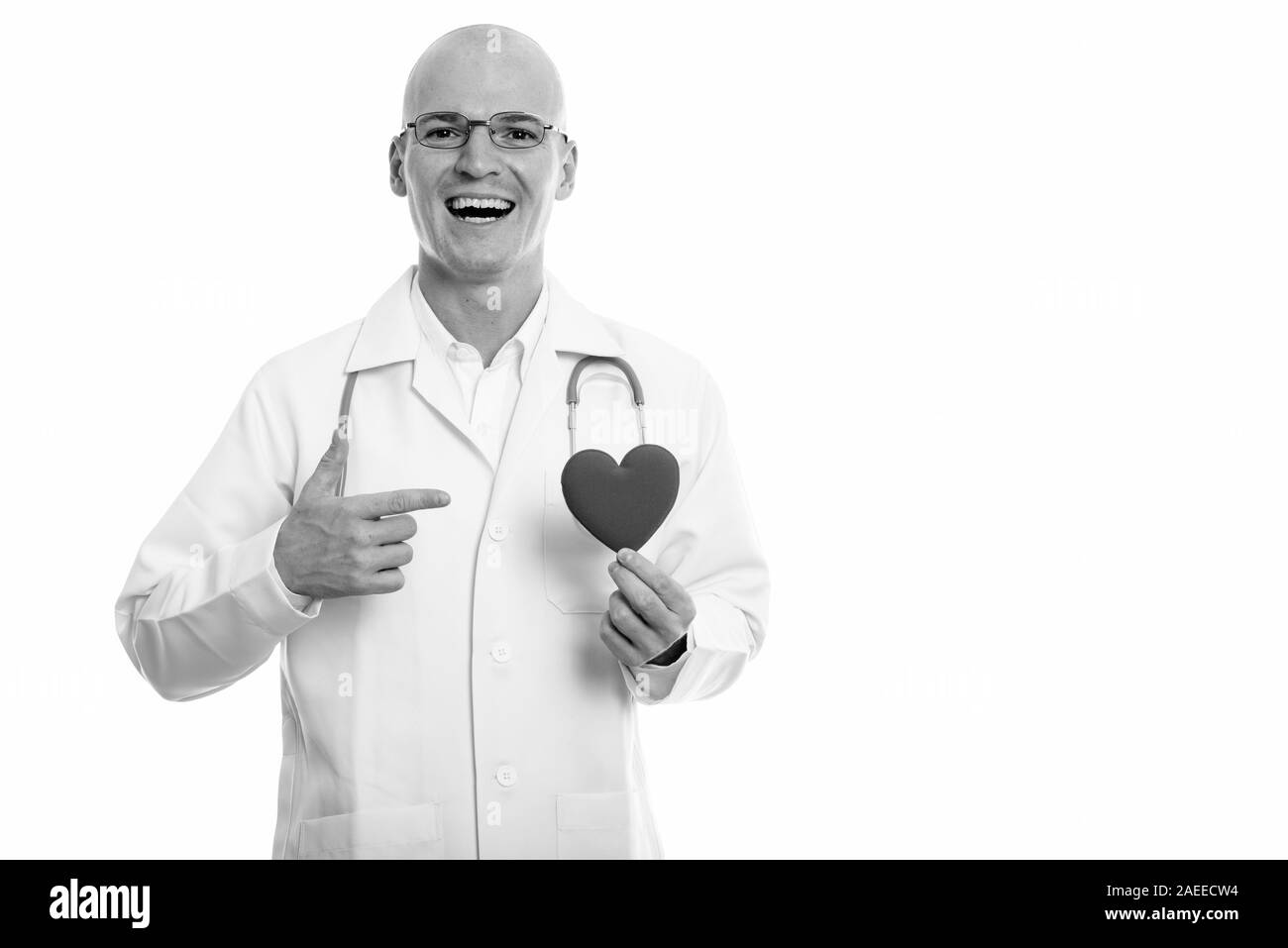 Young happy bald man doctor smiling while holding and pointing at red ...