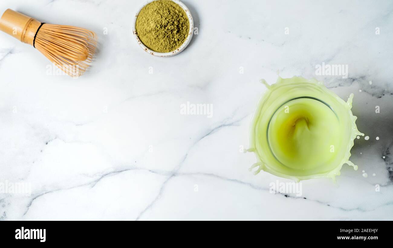 Homemade iced matcha latte with splashes over white marble background ...