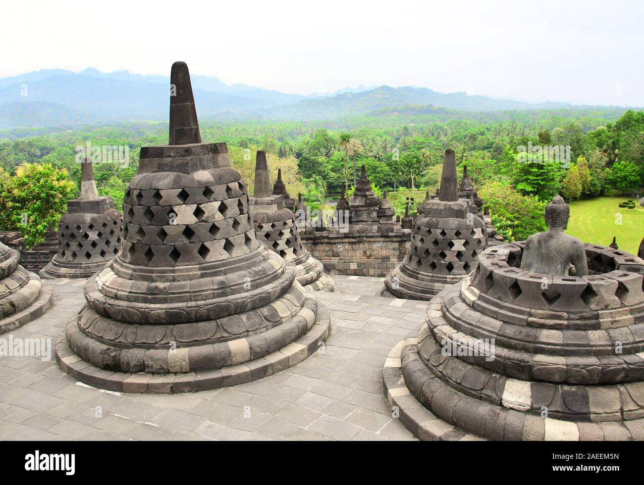 Ancient stupas and statue of a meditating Buddha in Borobudur Buddhist ...