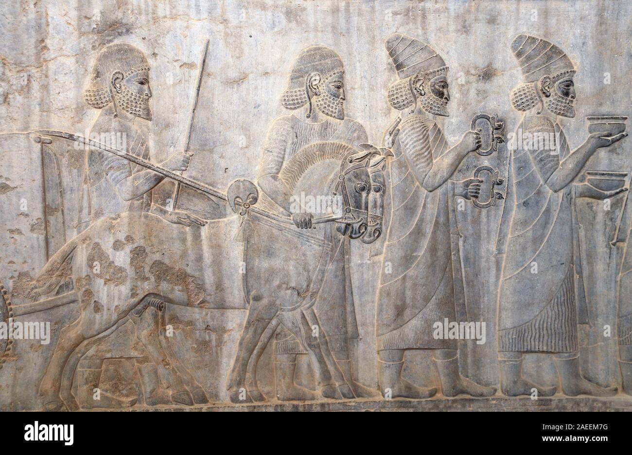 Ancient wall with bas-relief with assyrian warriors, horses and foreign ...