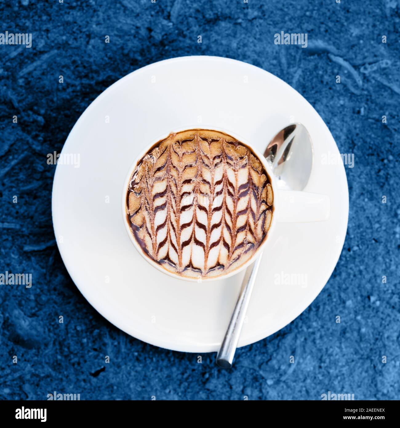 Overhead view of cafe latte with craft design on it toned in blue ...