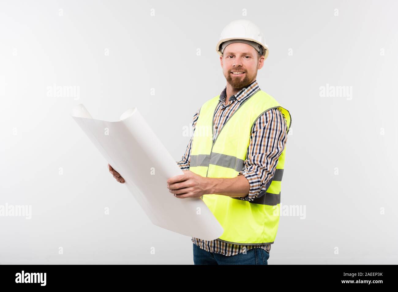 Successful young foreman in helmet and workwear holding paper with ...