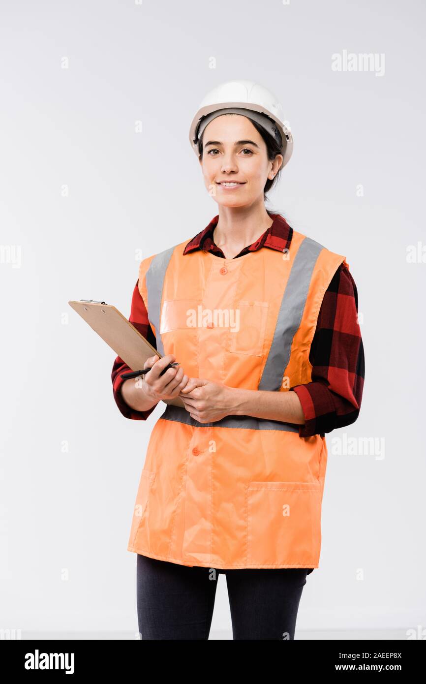 Successful female engineer in helmet and orange jacket holding ...