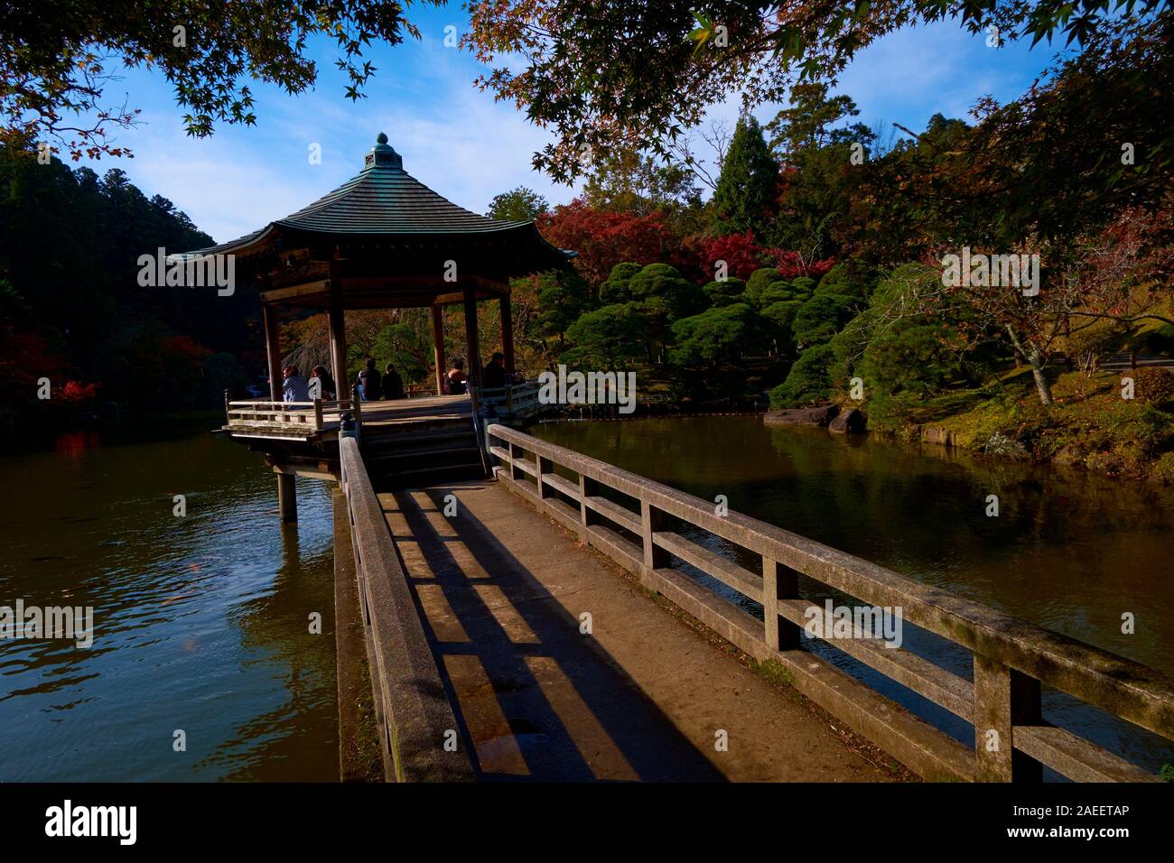 A traditional pagoda at the end of a small pier at a lake with autumn ...