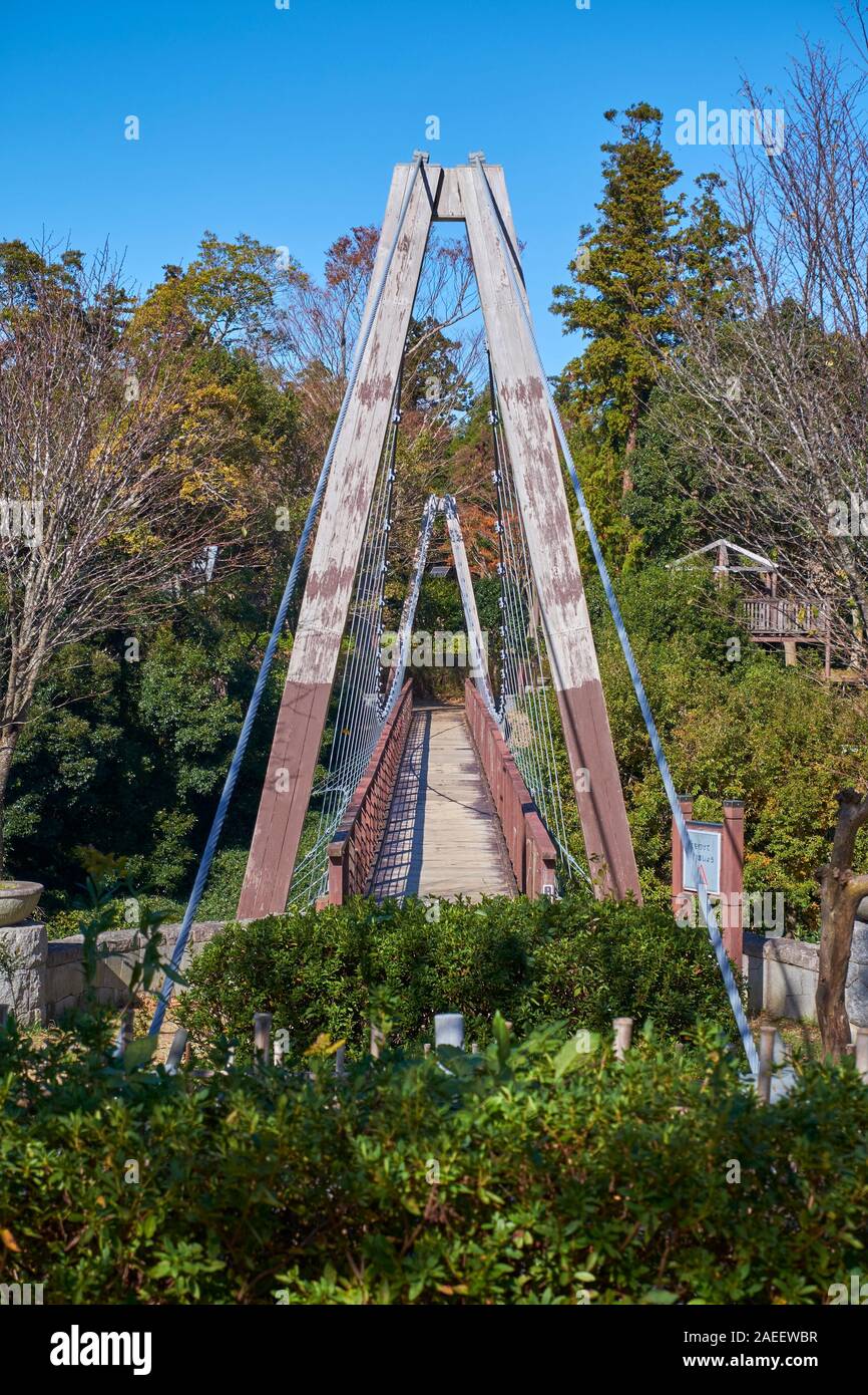 A modern wood and steel cable pedestrian bridge in the Sakatagaike ...