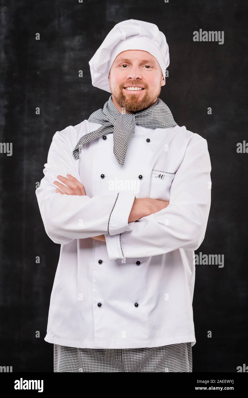Young smiling male chef crossing arms by chest while looking at you ...