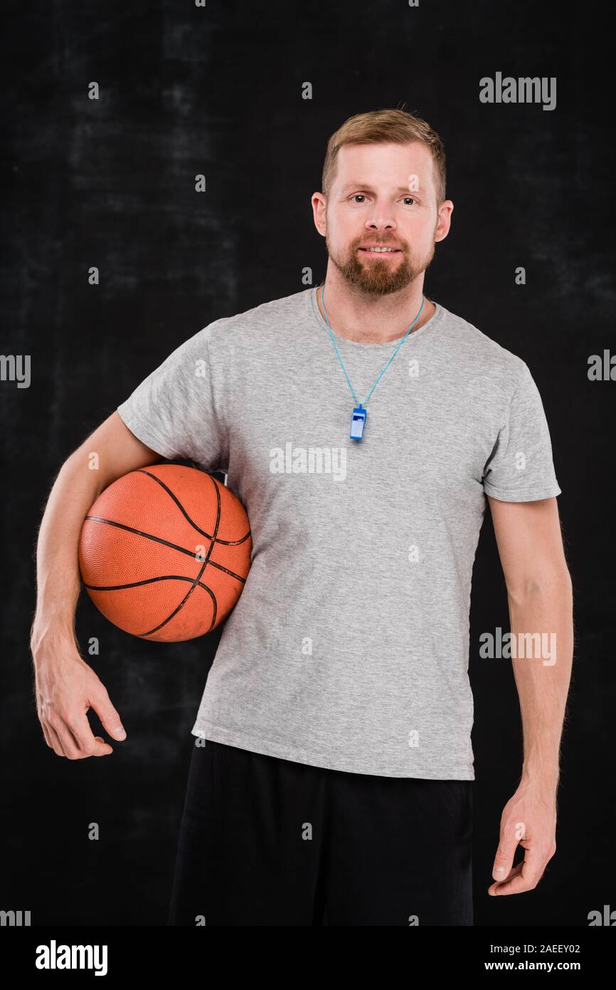 Young professional basketball trainer with ball standing in front of ...