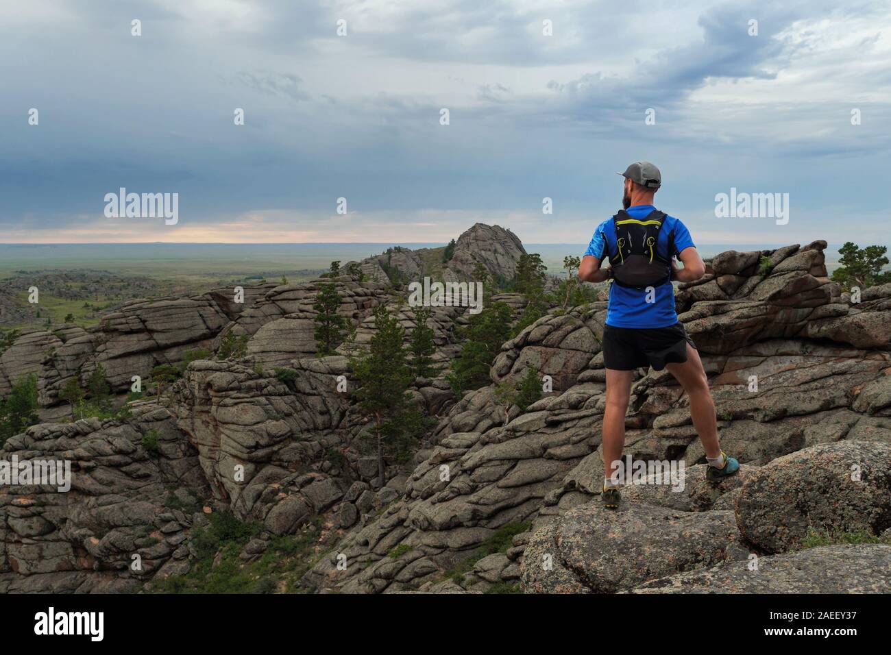 Male runner standing on the edge of a mountain cliff and looking at the ...