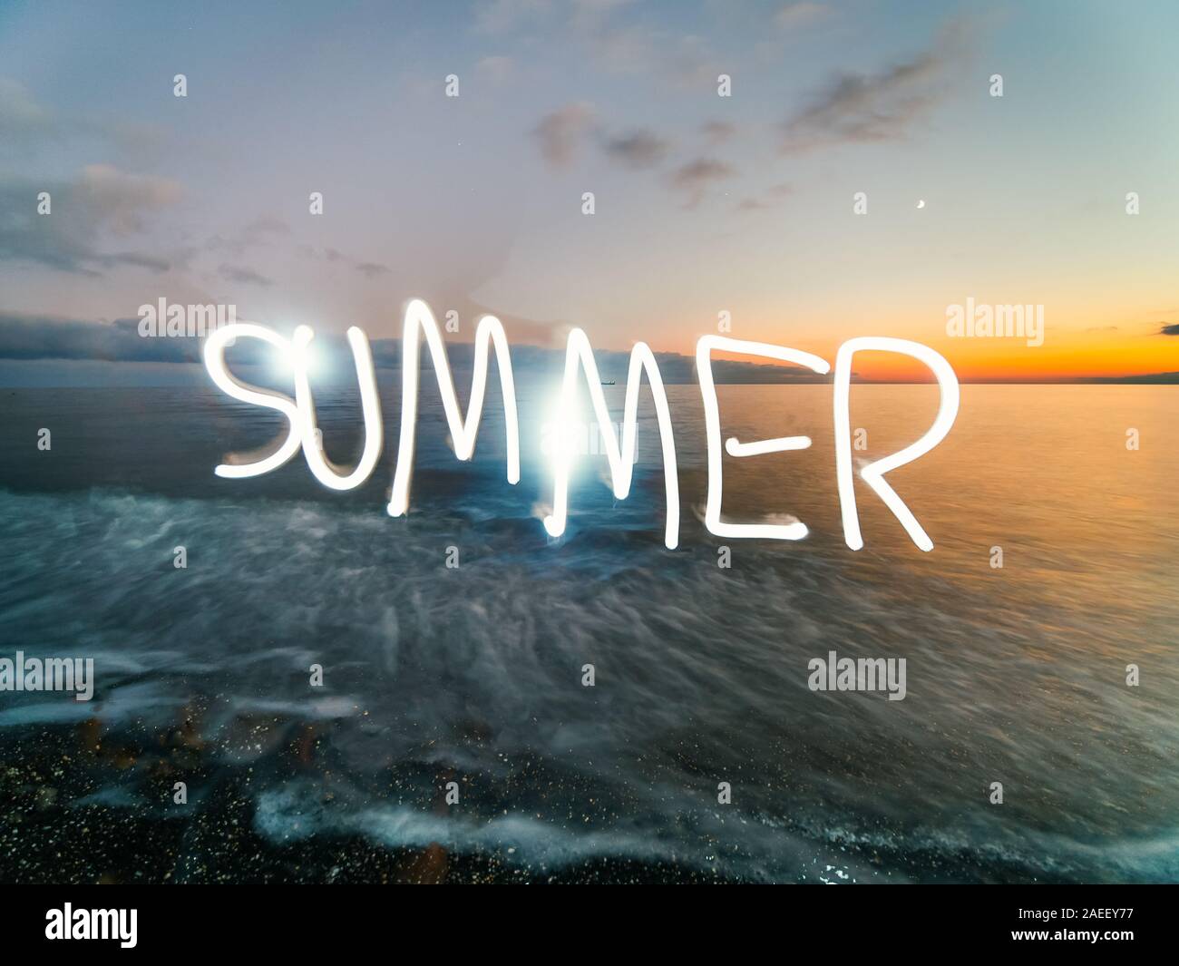 Summer letters made with flashlight or light pen over sea castline in ...