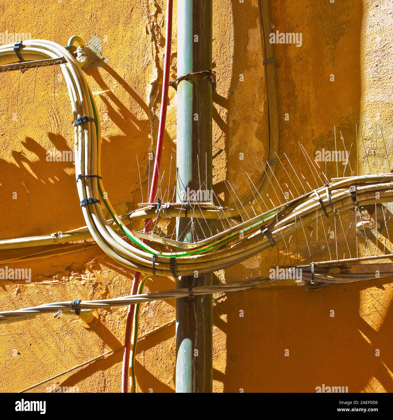 Electrical power cables and telephone cables against an old brick and ...